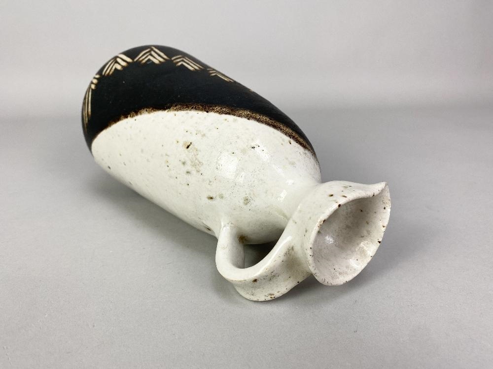 Barbara Cass | a stoneware bottle with side handle partially covered in ...