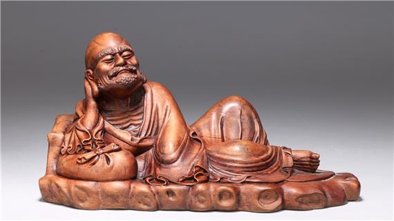 Chinese School | Chinese carved hardwood reclining Lohan; holding his ...
