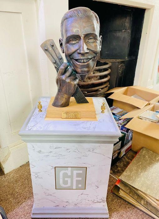 Graham High | A bronze bust of George Formby holding the neck of his ...